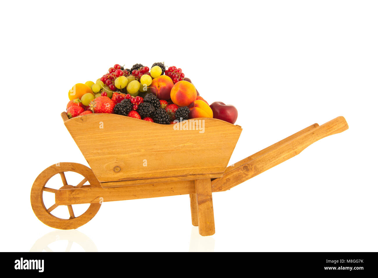 Wooden wheel barrow with fresh summer fruit isolated over white ...