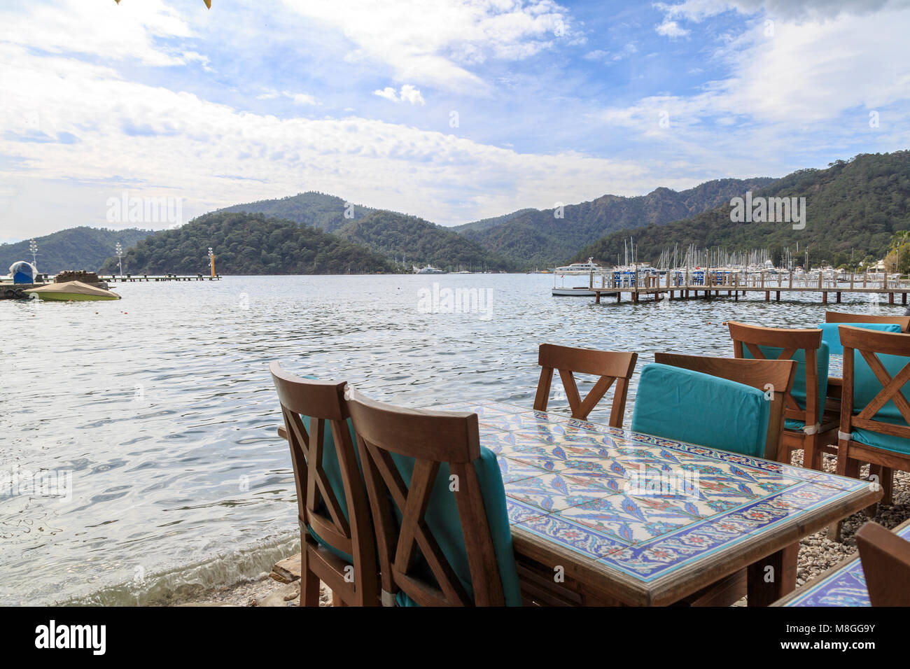 Table with chairs on gocek beach with mountains in gocek, Turkey Stock ...