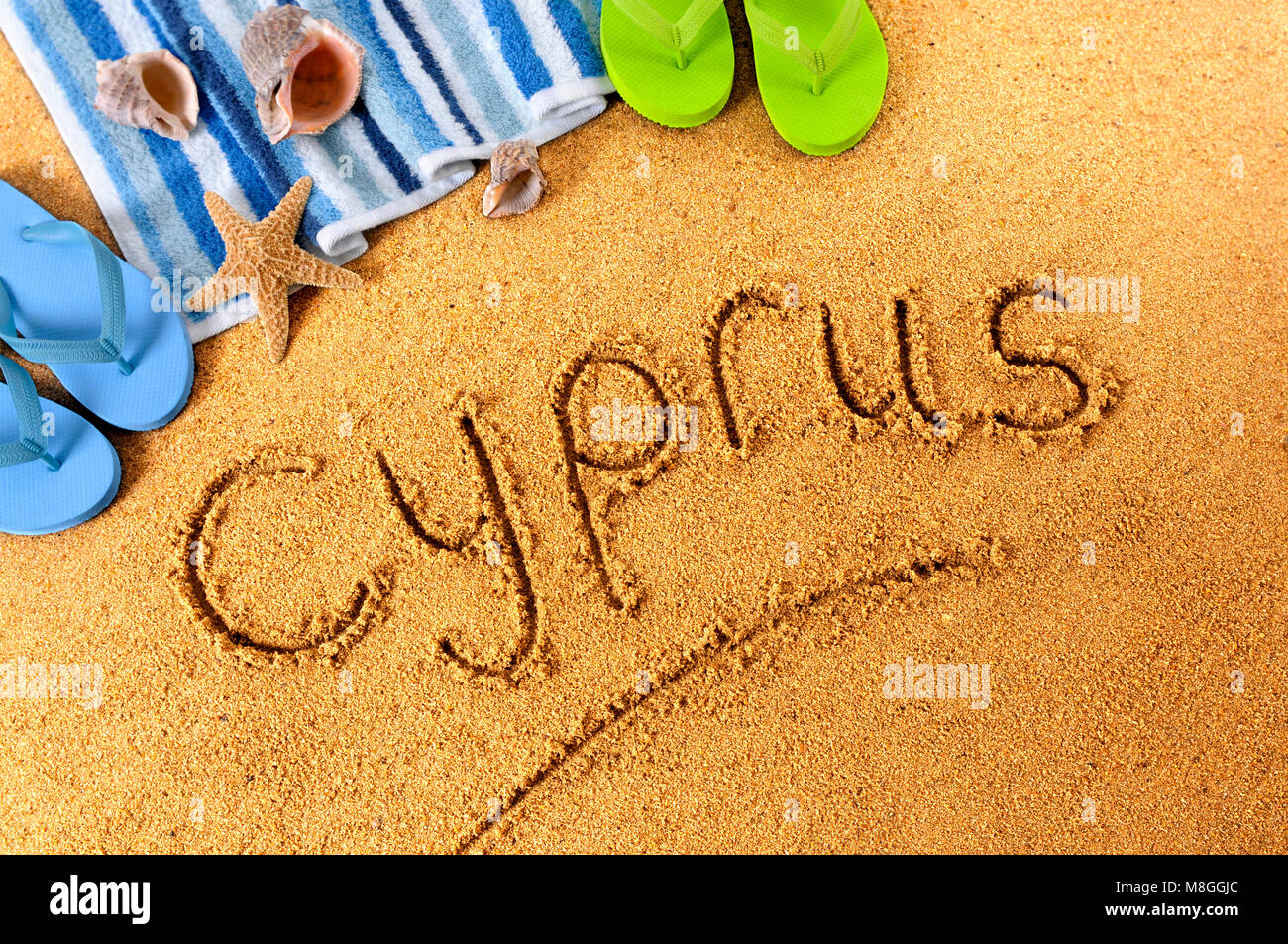 The word Cyprus written on a sandy beach, with beach towel, starfish ...