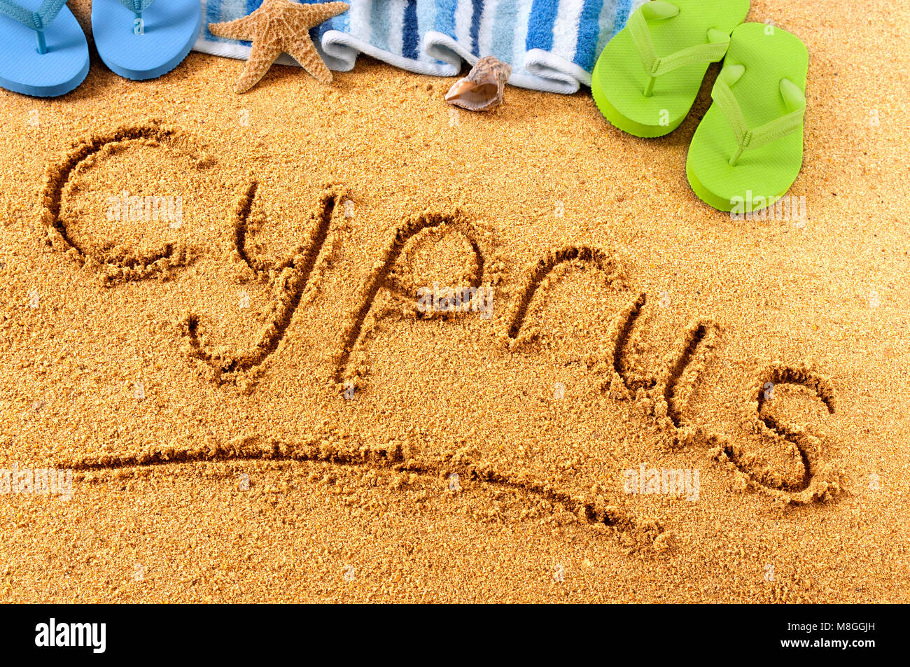 The word Cyprus written on a sandy beach, with beach towel, starfish ...