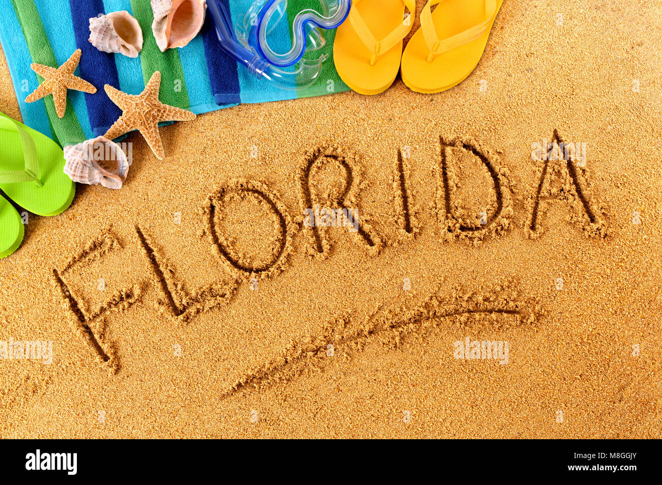 The word Florida written on a sandy beach, with scuba mask, beach towel ...