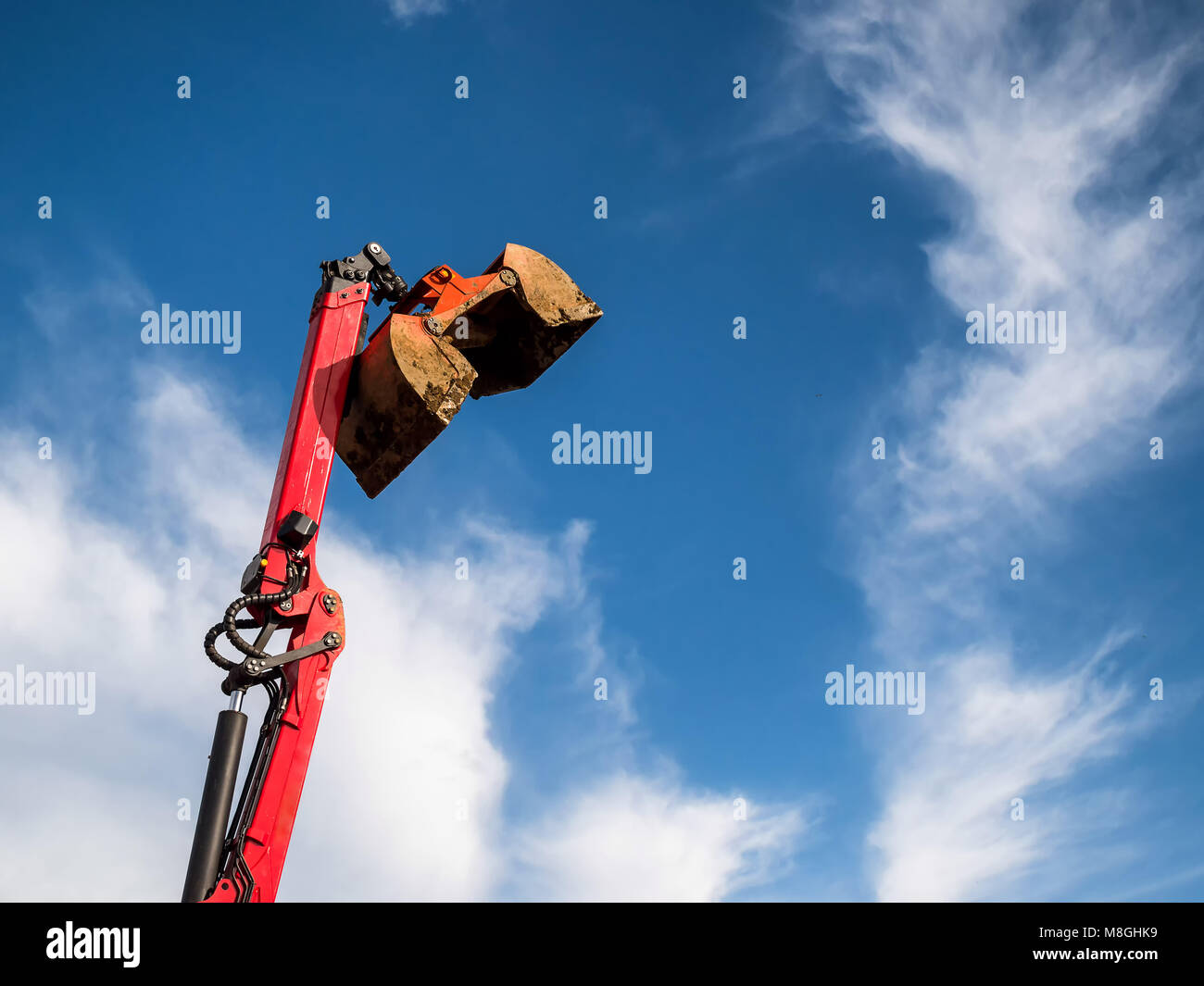 A large red construction excavator bucket over blue sky ready for ...