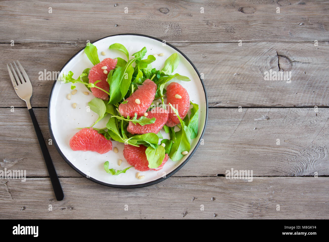 Fresh citrus salad with arugula, grapefruit and pine nuts on wooden ...