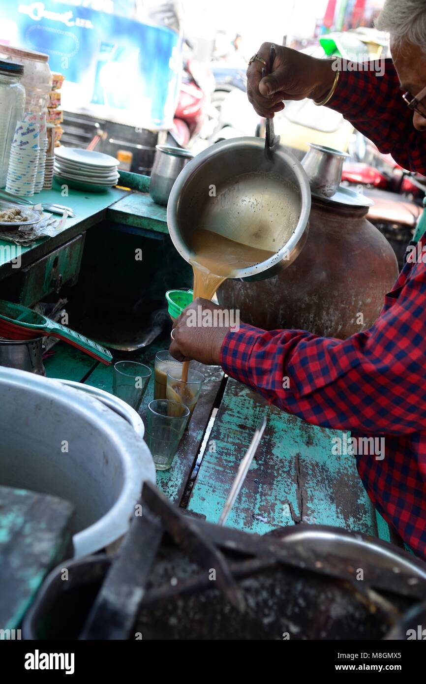 Indian man Chai Wallah pouring chai into a glass at a street food stall ...