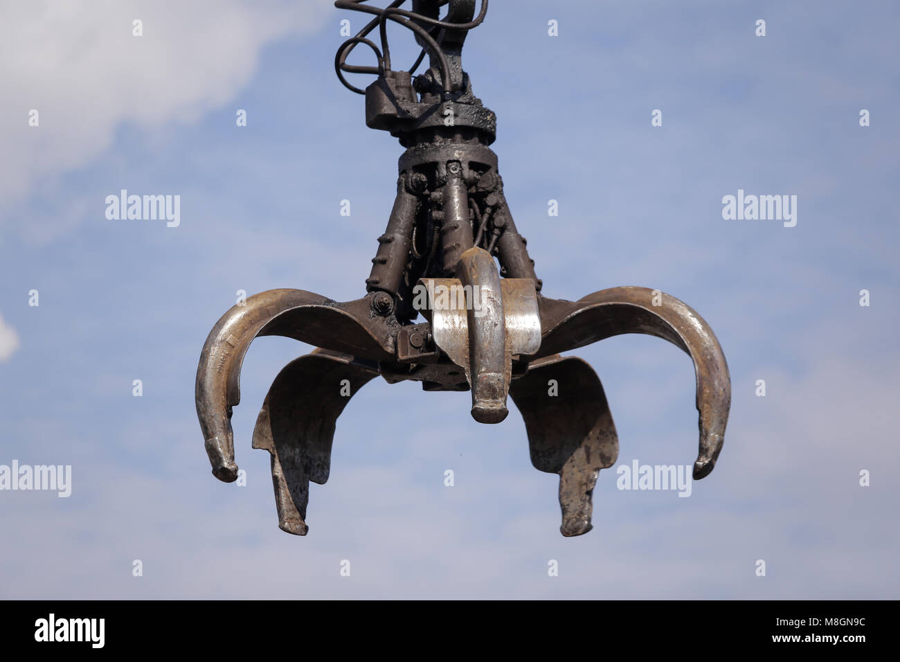 A worker uses a claw excavator to load shredded metal from cars at a ...
