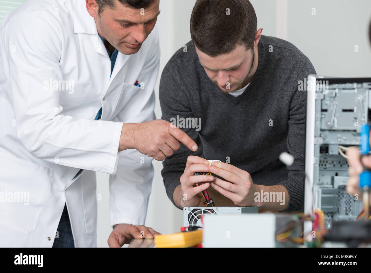 teacher with student in technology repairing computer Stock Photo - Alamy