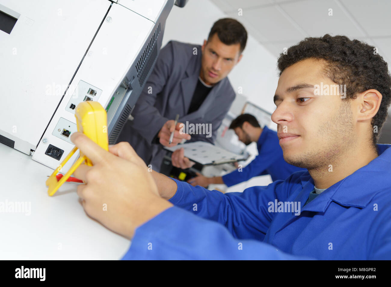 young technician using mutimeter under teachers supervision Stock Photo ...