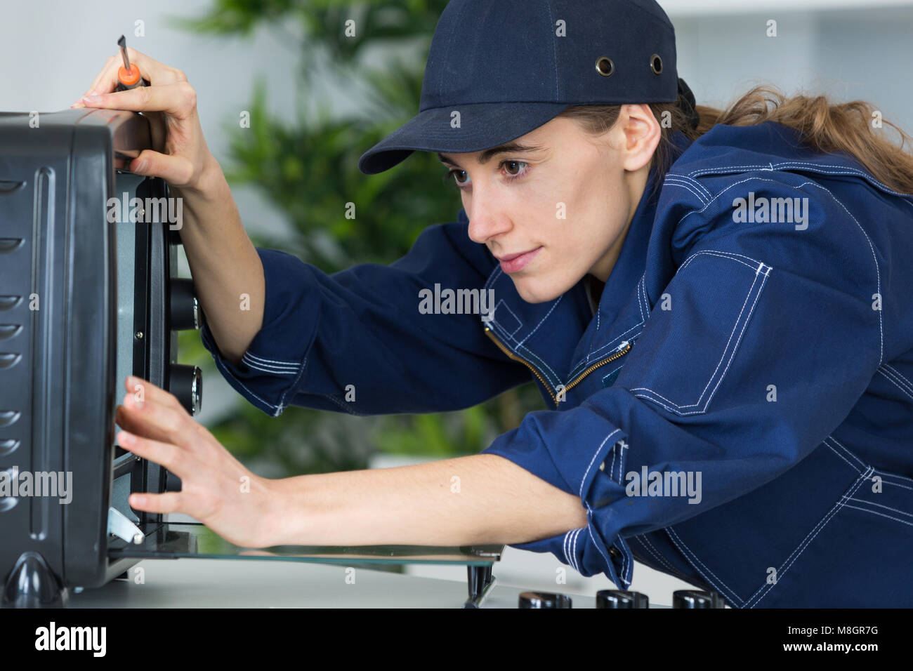 young female technician repairing oven in kitchen Stock Photo - Alamy