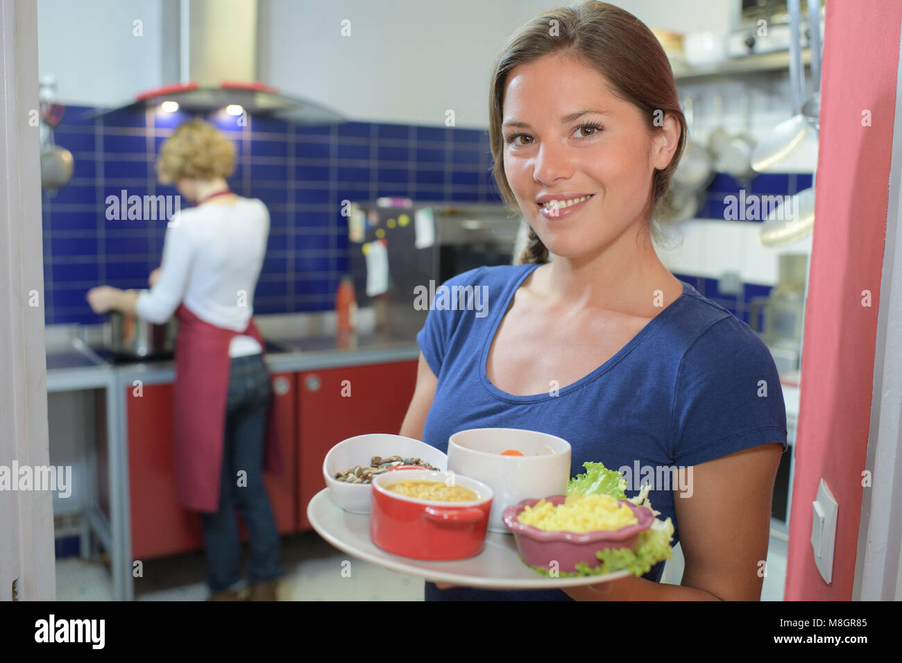 waitress showing dishes to the camera and chef in background Stock ...