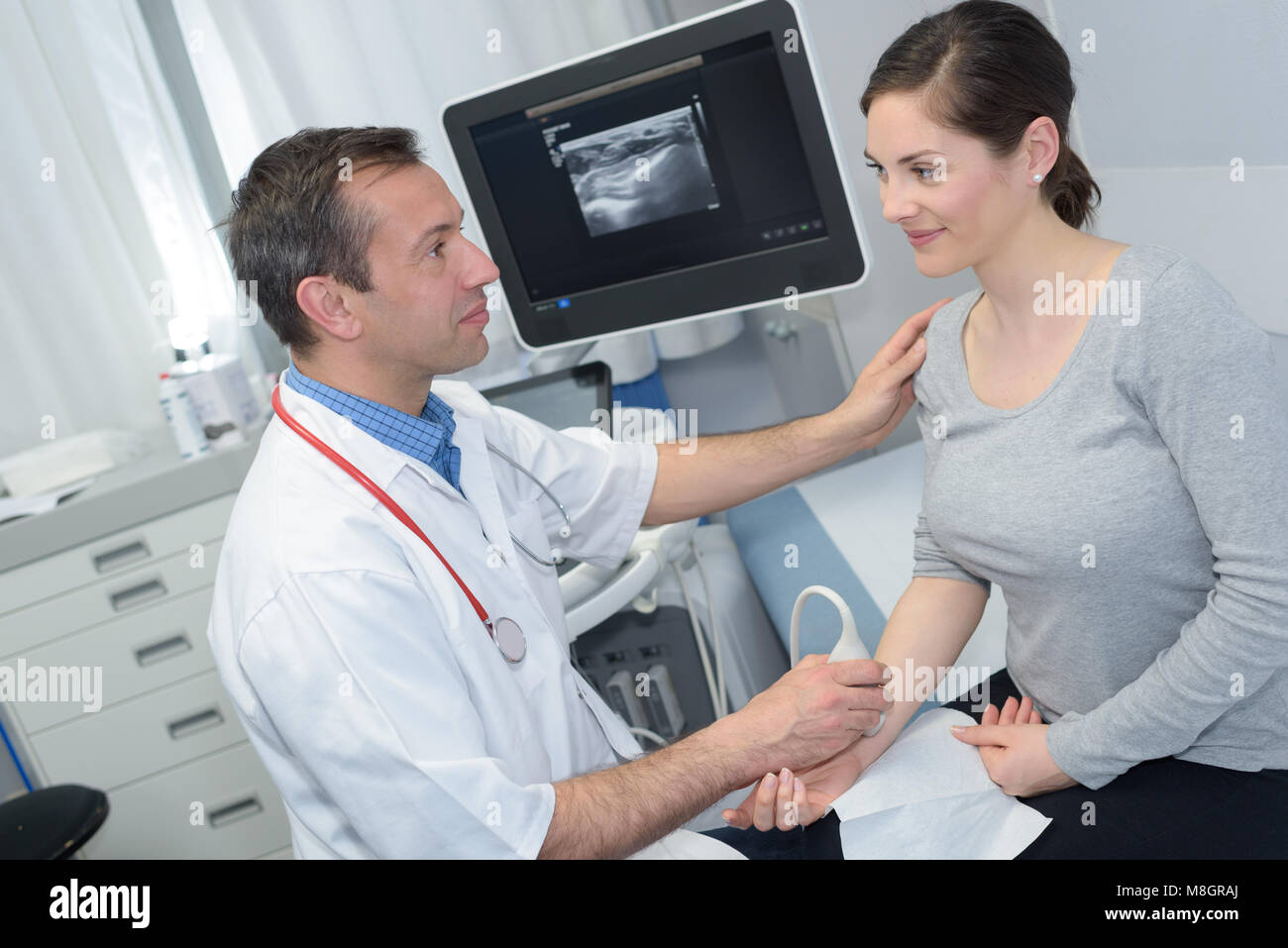 doctor with female patient undergoing arm echography Stock Photo - Alamy