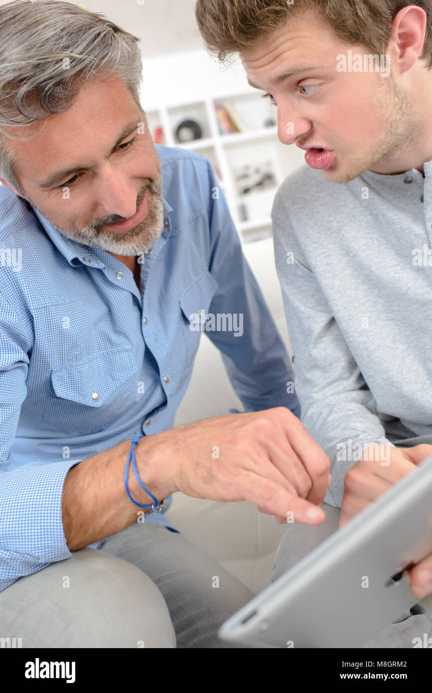 Father pointing to tablet screen, son shouting at him Stock Photo - Alamy
