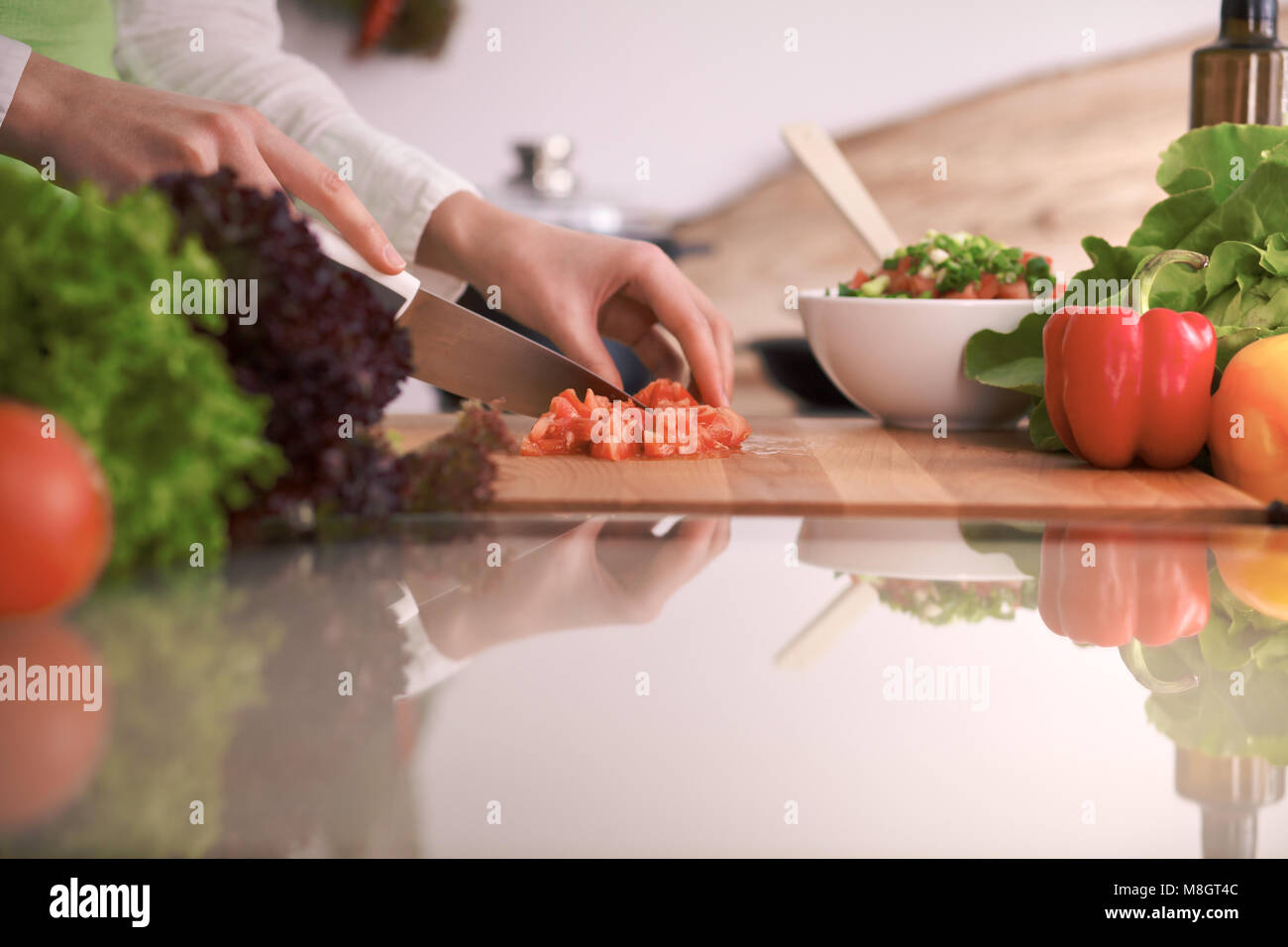 Close Up of human hands cooking vegetable salad in kitchen on the glass ...