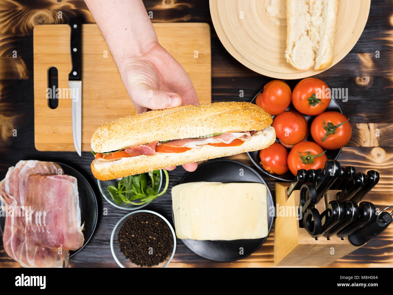 Hand holds a sandwitch over the kitchen table Stock Photo - Alamy