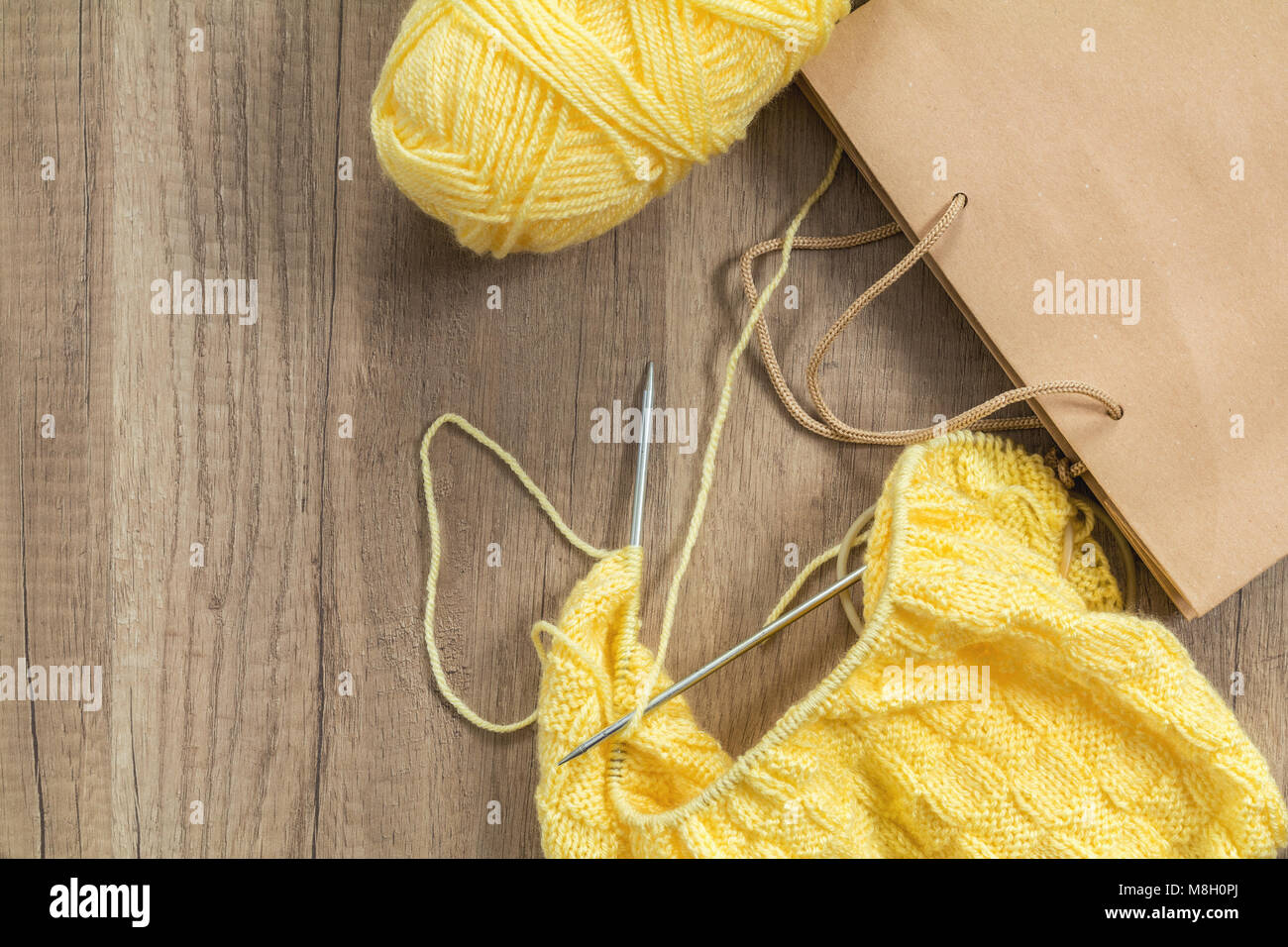 Light yellow knitting wool and knitting needles on wooden background ...