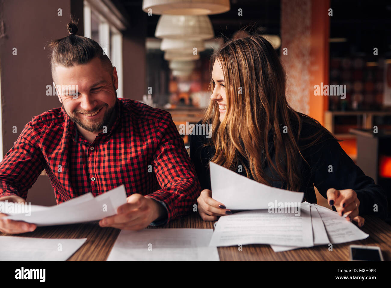 colleagues discuss documents sitting in a cafe Stock Photo - Alamy