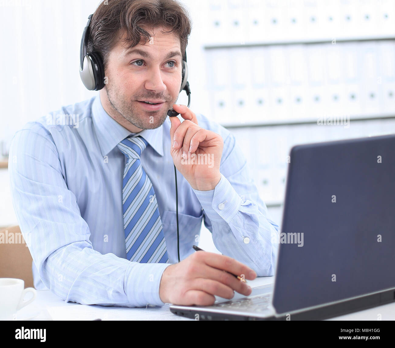 Happy young man working at callcenter, using headset Stock Photo - Alamy