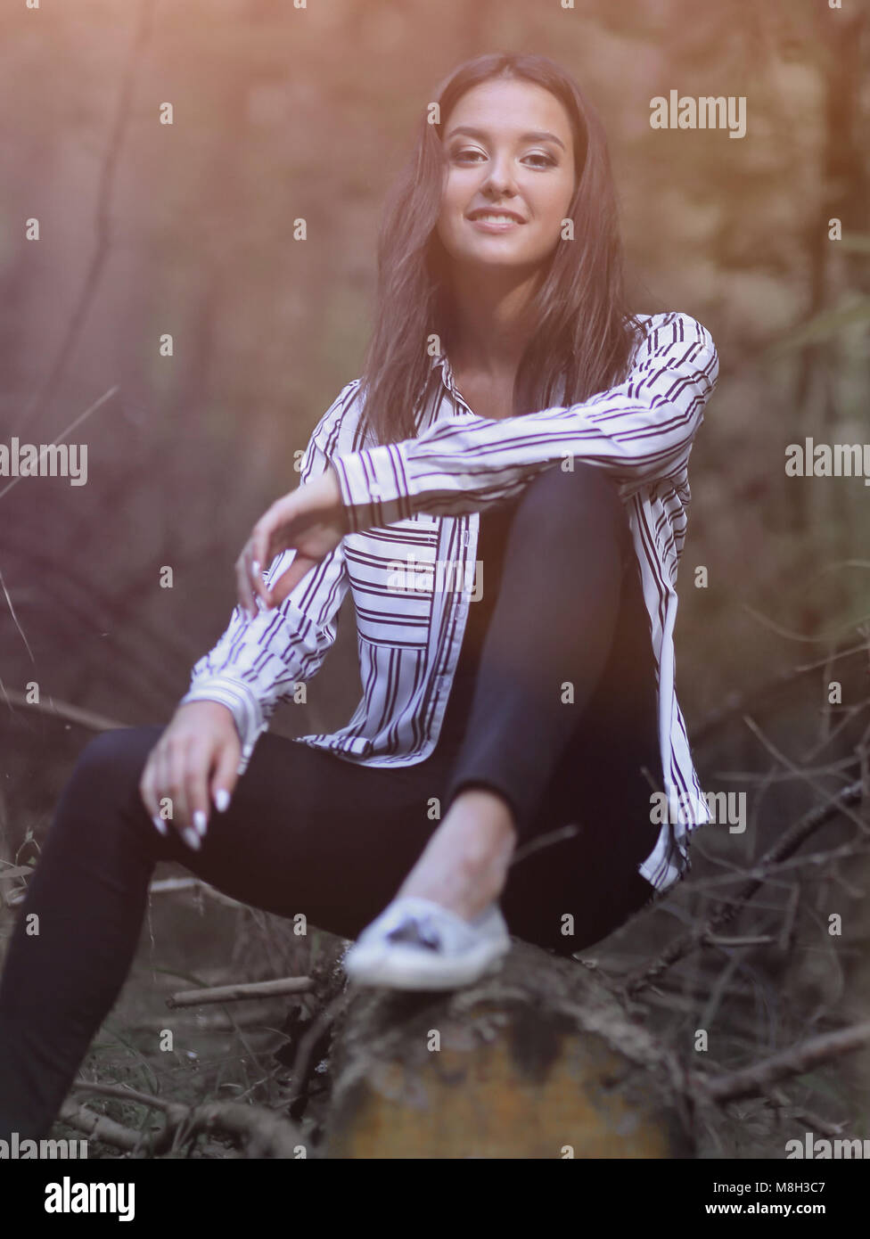 beautiful young woman sitting on a log Stock Photo - Alamy