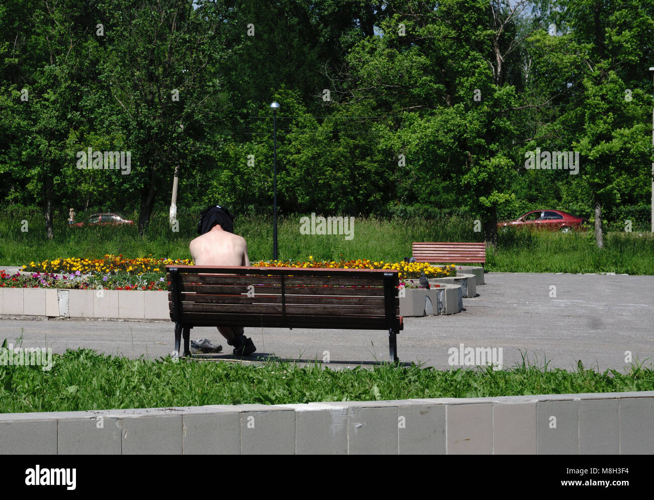 sunbathes in the sun sitting on the bench Stock Photo - Alamy