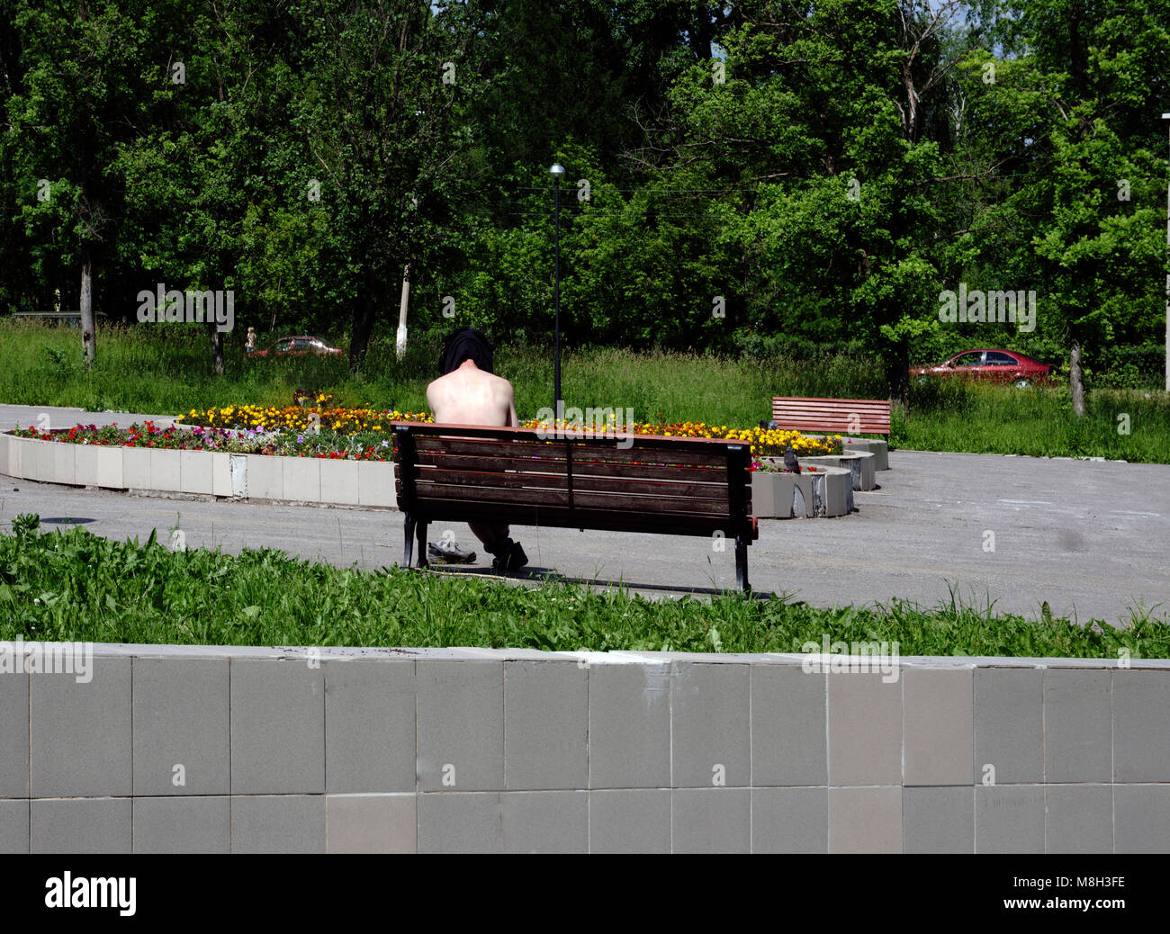 a man sunbathes in the sun sitting on the bench Stock Photo - Alamy