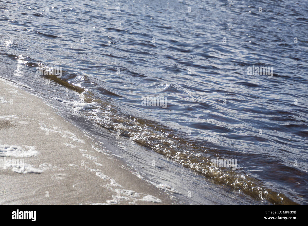 Waves wash over dark sand on the beach Stock Photo - Alamy