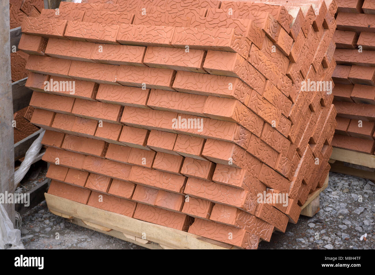 Red clay building bricks stacked on pallets still wrapped in their ...