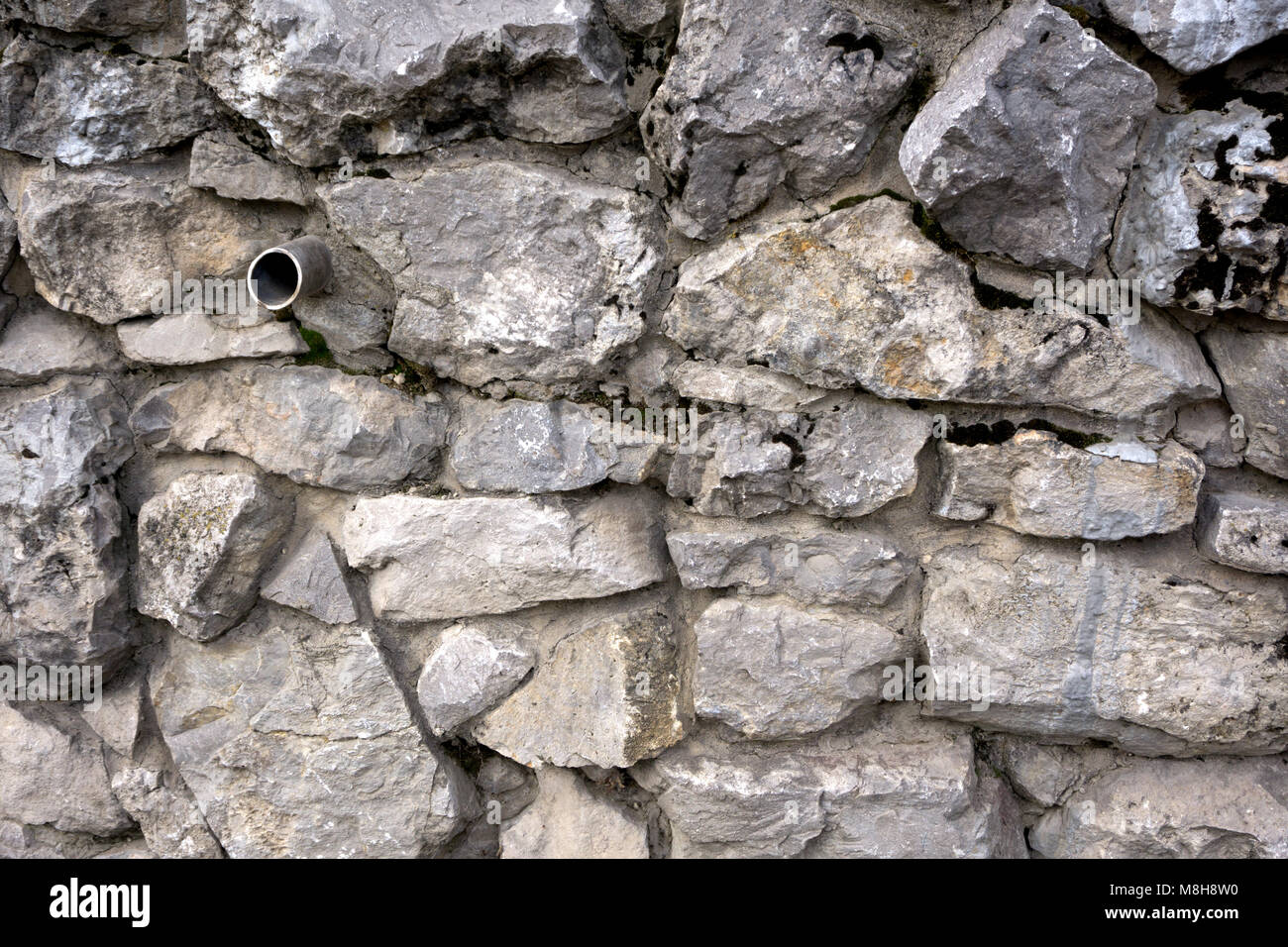 Single water pipe protruding from a cracked white plaster wall with ...