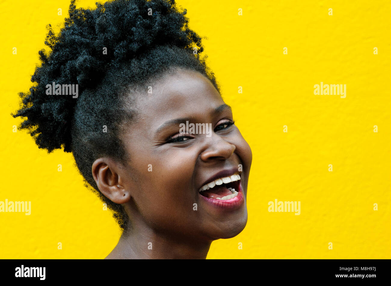 Portrait of a beautiful black colombian model laughing on a yellow ...