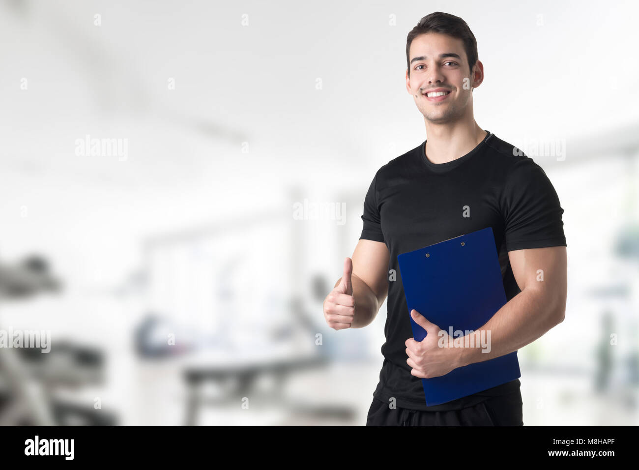 Personal trainer in a gym holding a notepad Stock Photo - Alamy