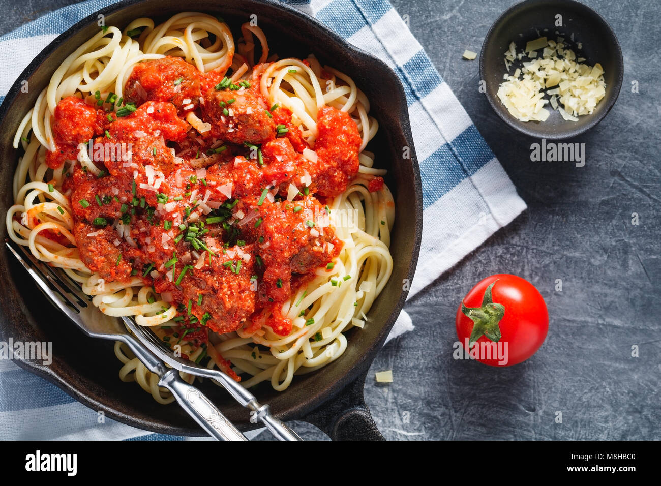Spaghetti with meatballs in tomato sauce and parmesan cheese in an iron ...