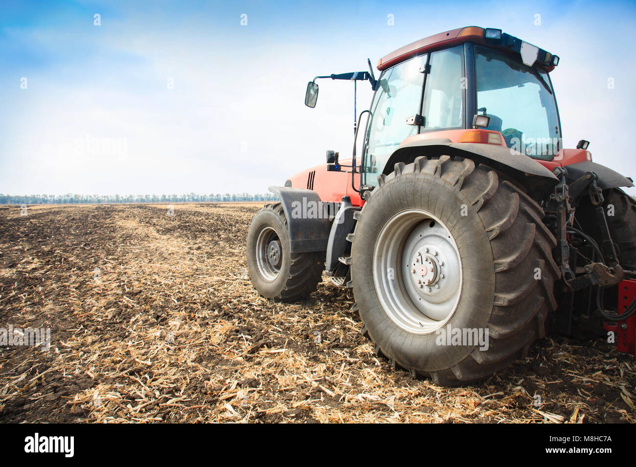 Modern red tractor in the field on a bright sunny day Stock Photo - Alamy