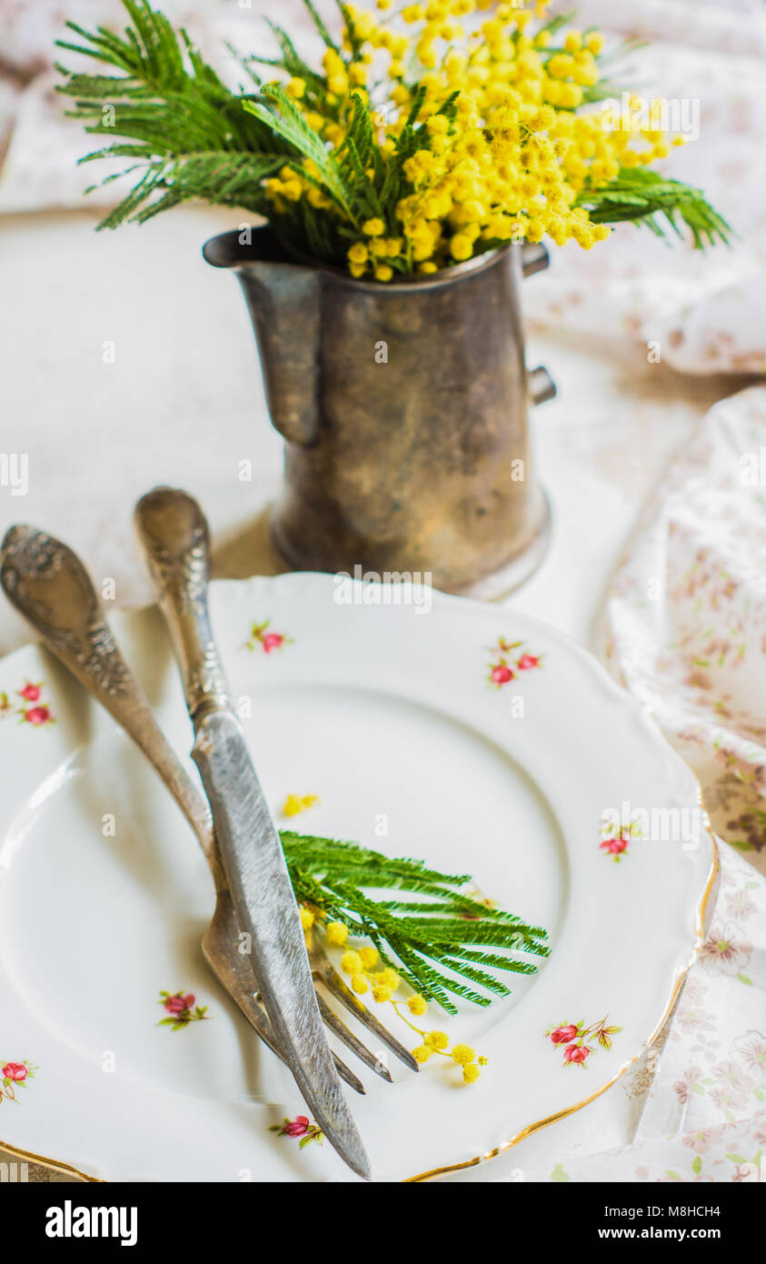 Spring festive dining table setting with yellow mimosa flowers, napkins ...