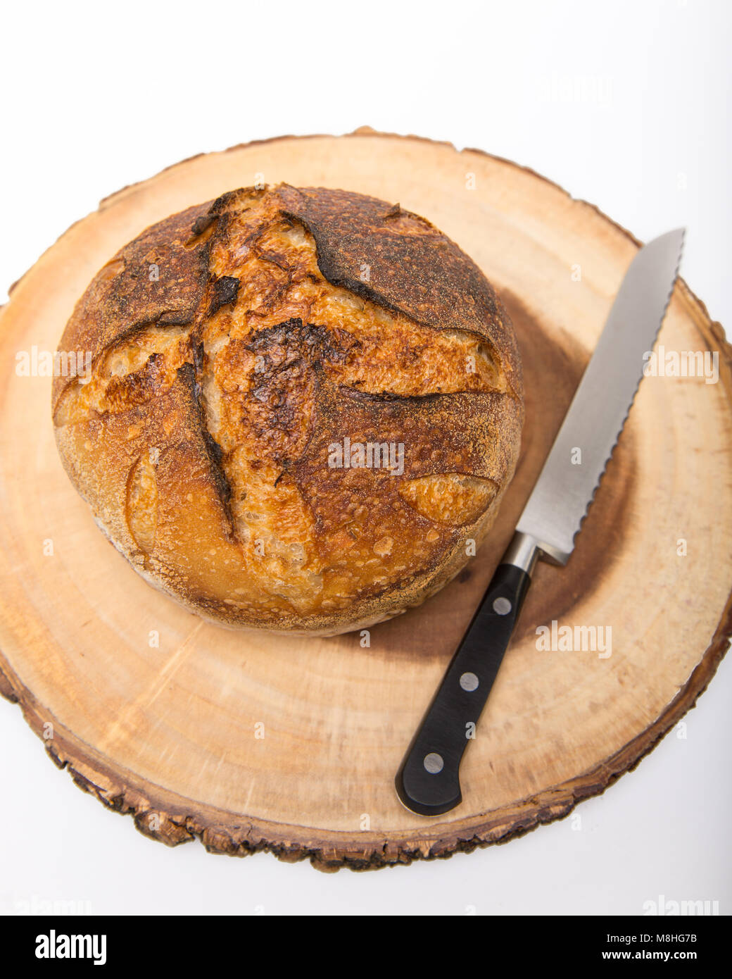 A fresh loaf of round artisan sourdough bread with a breaqd knife Stock ...