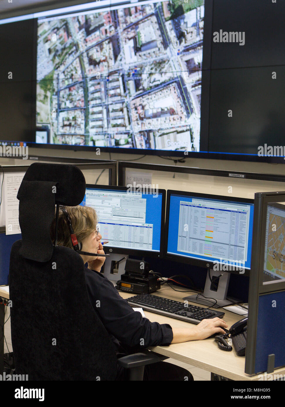 Police officers control the emergency calls from their control area ...