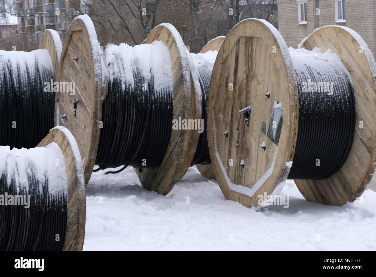 black wire electric cable with wooden coil of electric cable under the ...