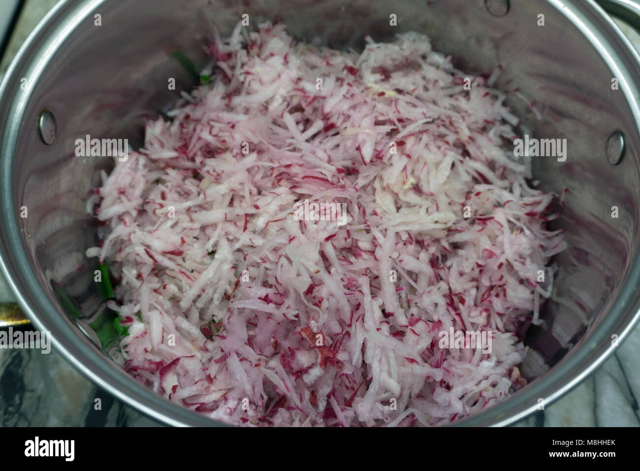 Mechanical kitchen grater is filled with shredded red radish Stock ...