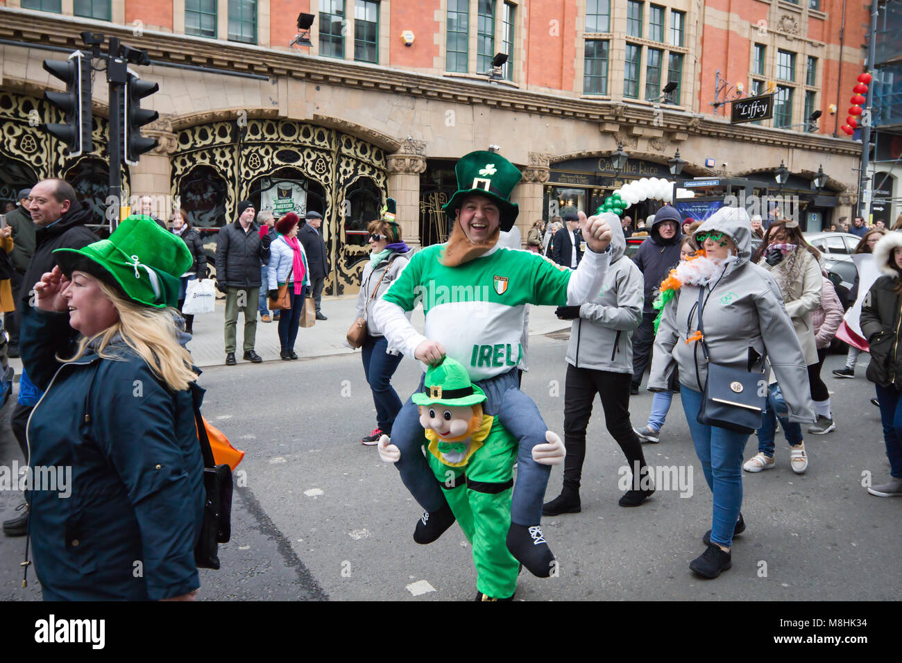 Liverpool, UK. 17th March 2018. Man being carried by a leprechaun at ...