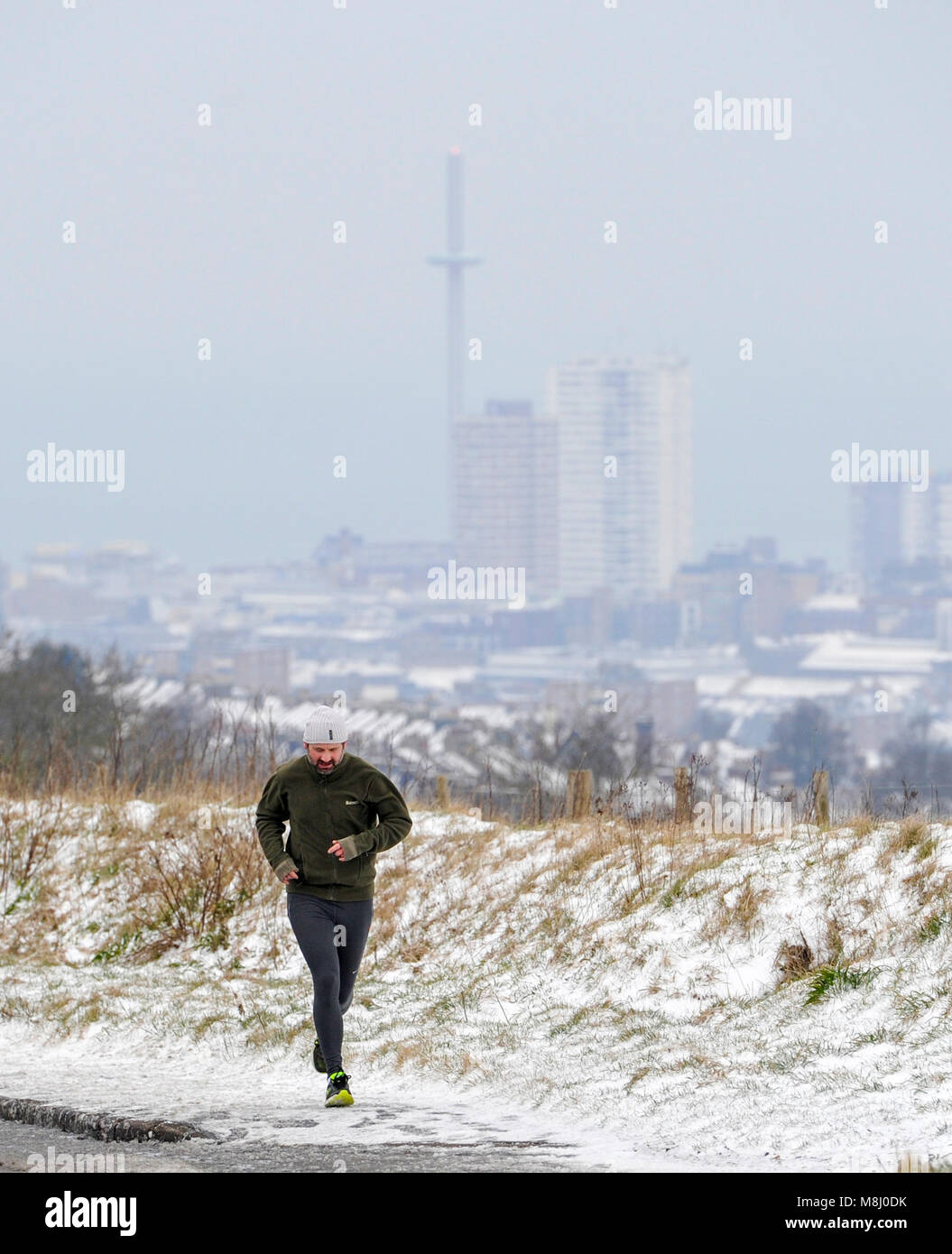 Brighton UK 18th March 2018 - A runner in the snow on the hills above ...