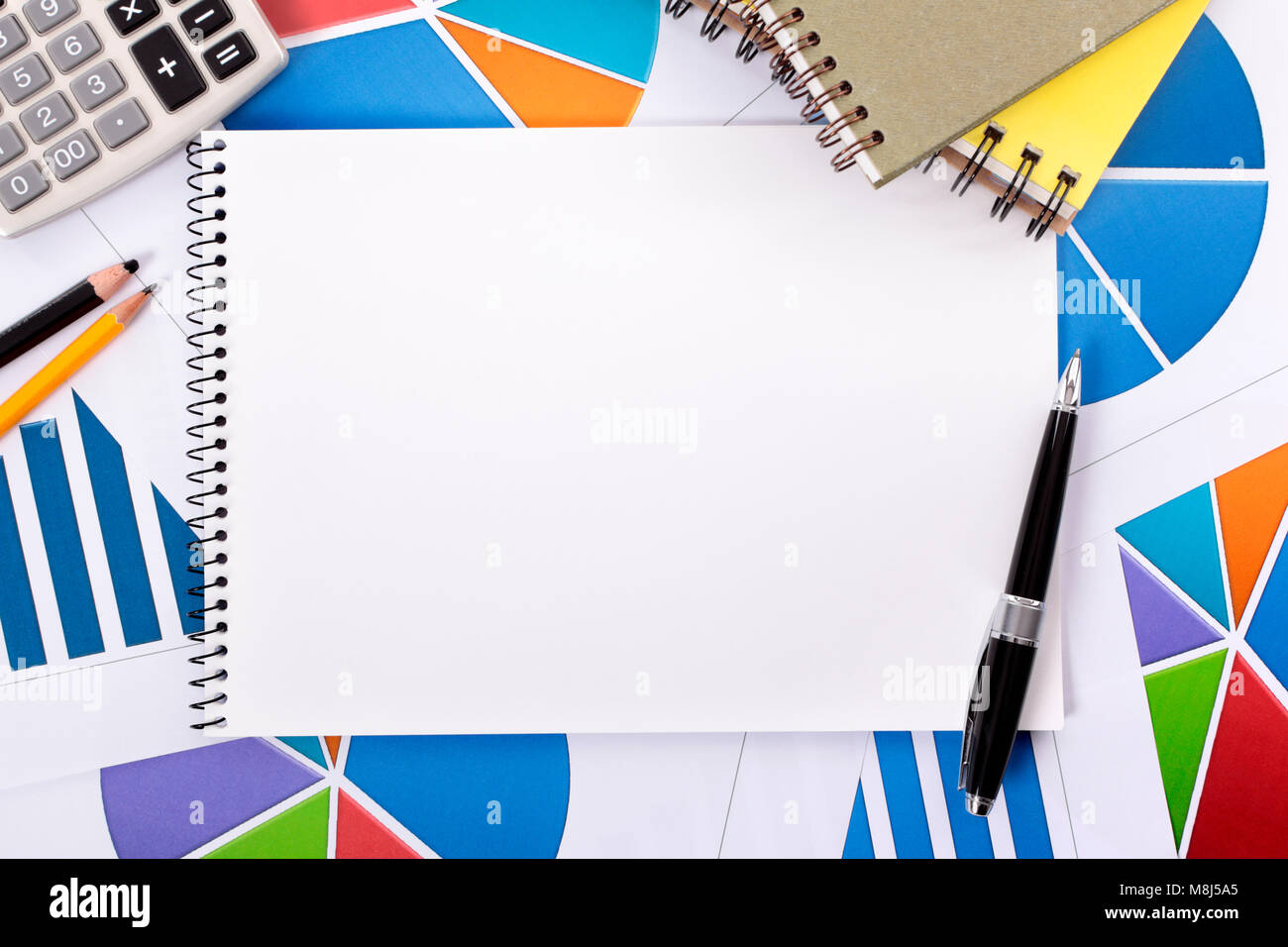 Blank folded notebook surrounded by various charts and graphs, pencils ...
