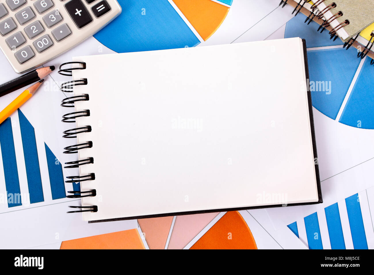 Blank folded notebook surrounded by various charts and graphs, pencils ...