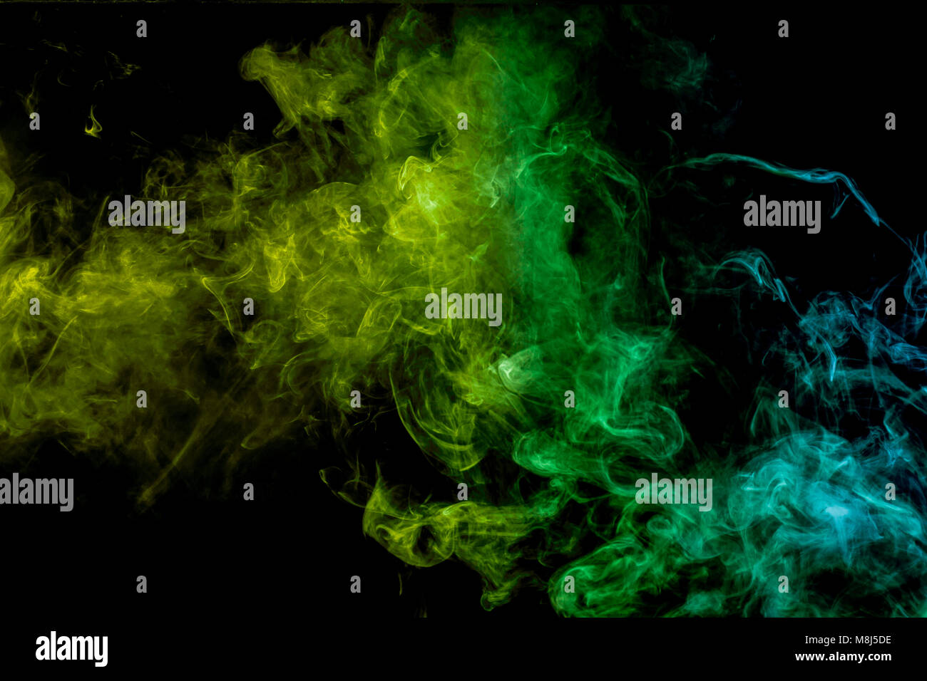 Dense multicolored smoke of green and blue colors on a black isolated ...