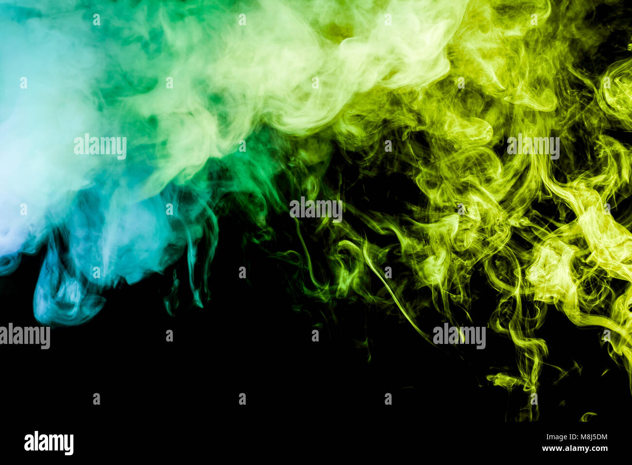 Dense multicolored smoke of green and blue colors on a black isolated ...