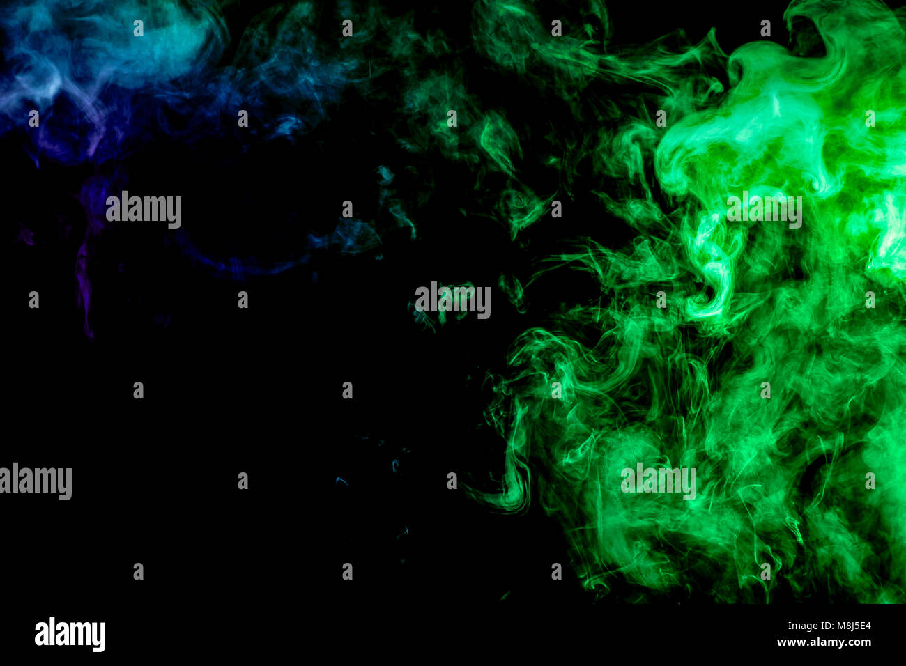Dense multicolored smoke of green and blue colors on a black isolated ...