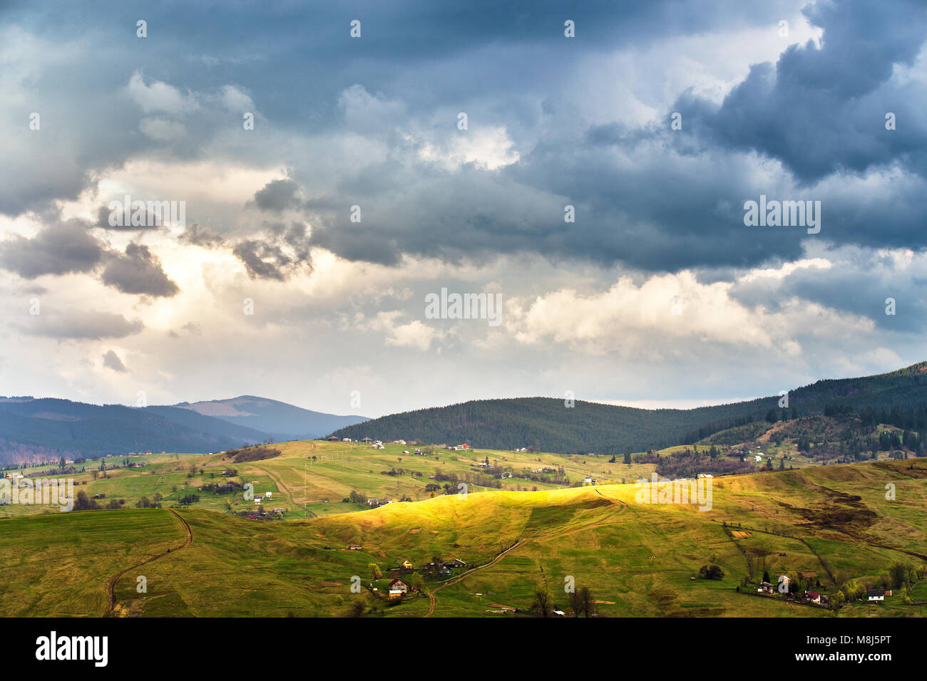 Green spring alpine scene. Mountain village on hillsides. Spring stormy ...