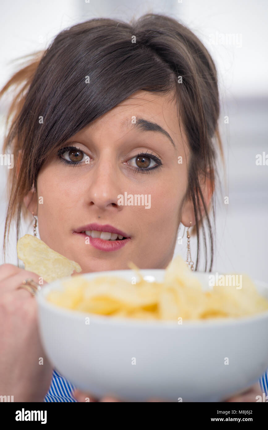 pretty young brunette woman eating chips Stock Photo - Alamy