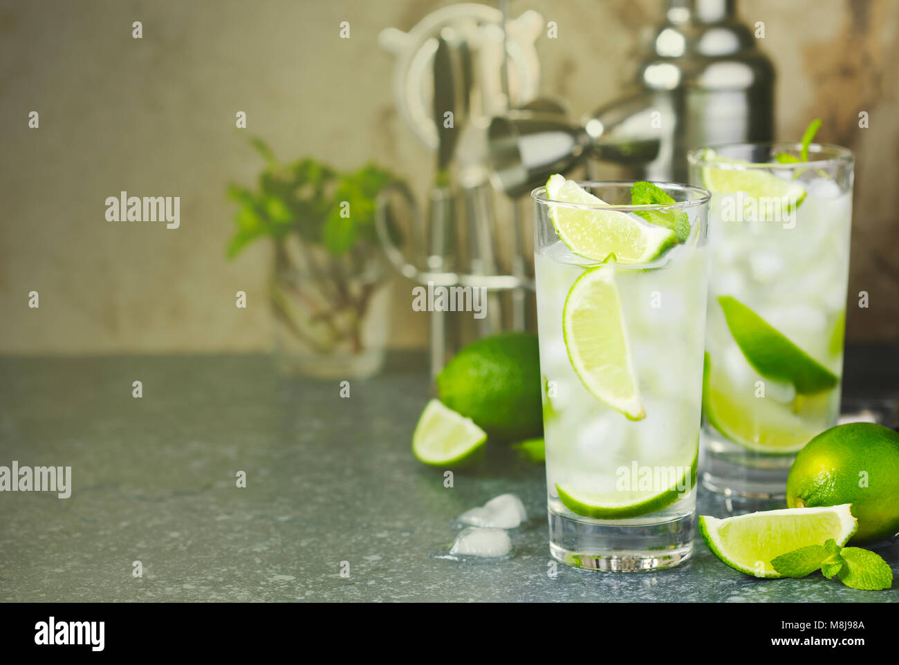 Mojito cocktail with lime and mint in glass on a stone table. Bar tools ...