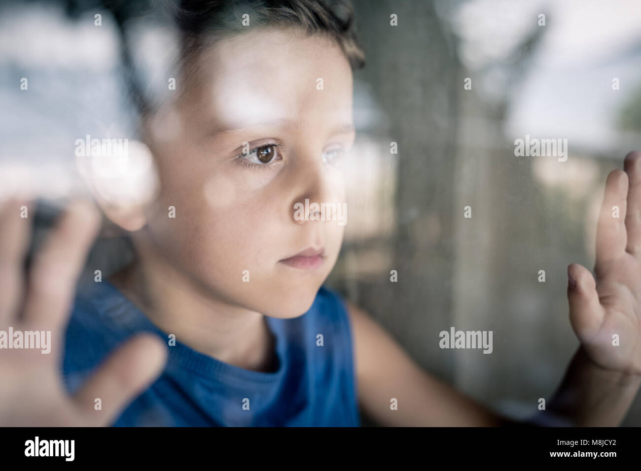 one sad little boy standing near the window at the day time. Concept of ...