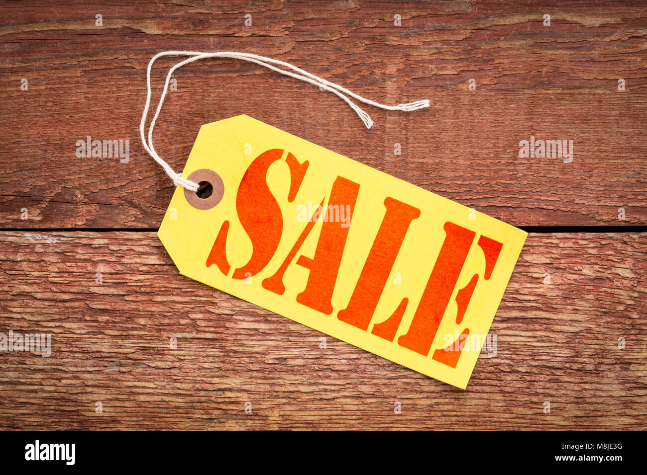 sale sign a yellow paper price tag against rustic red painted wood ...