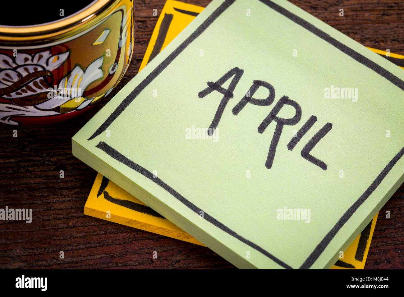 April - handwriting in black ink on a sticky note with a cup of coffee ...