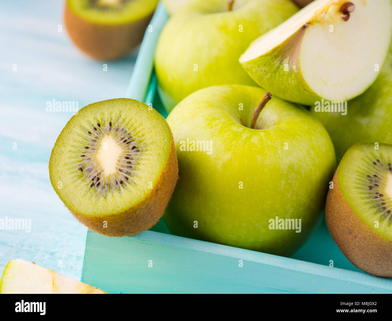 Green apples and kiwi on turquoise background Stock Photo - Alamy