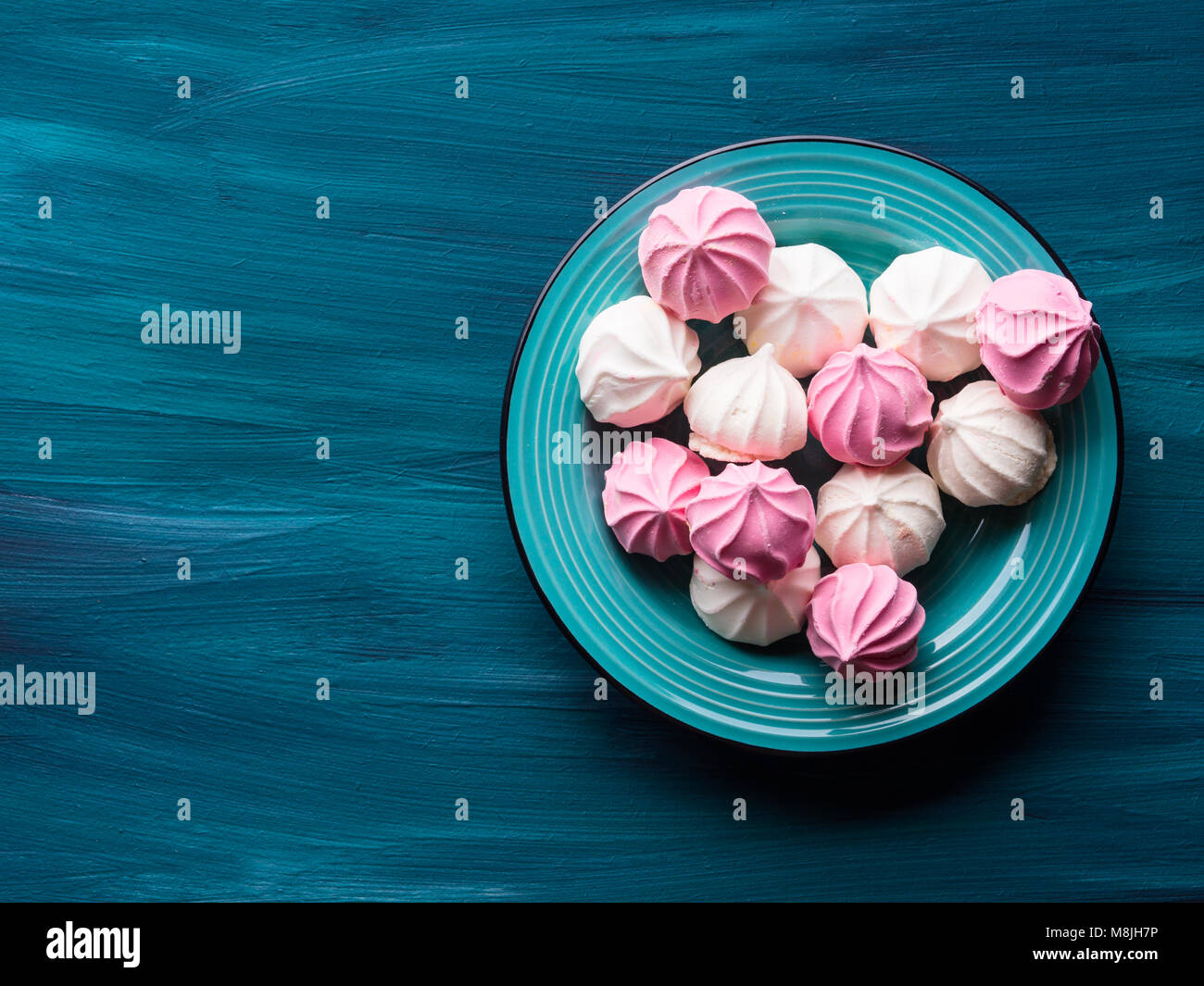 Pastel color pink and white meringue on green background Stock Photo ...